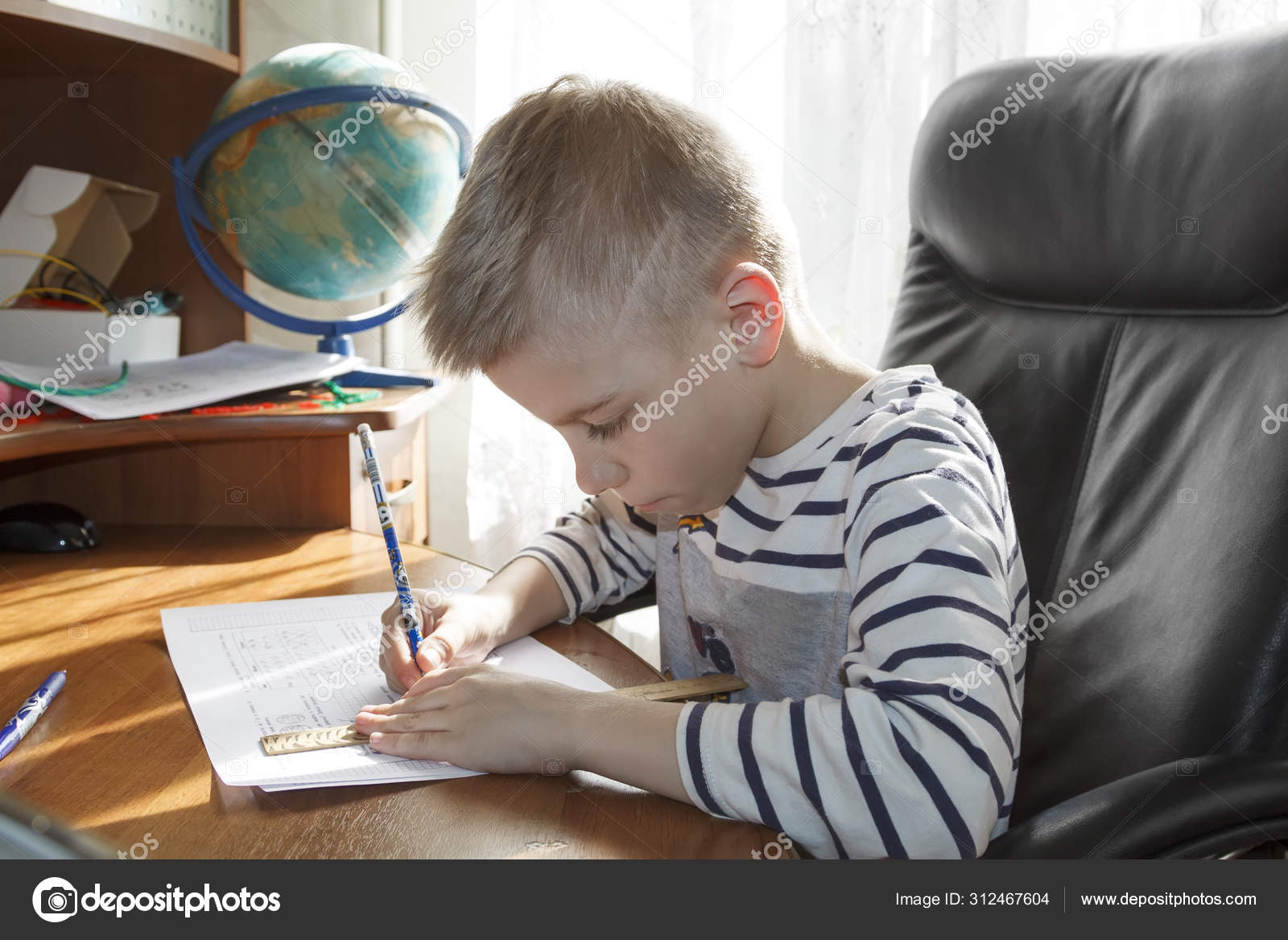 Boy is doing math homework. he draws a pencil on the ruler of th Stock ...