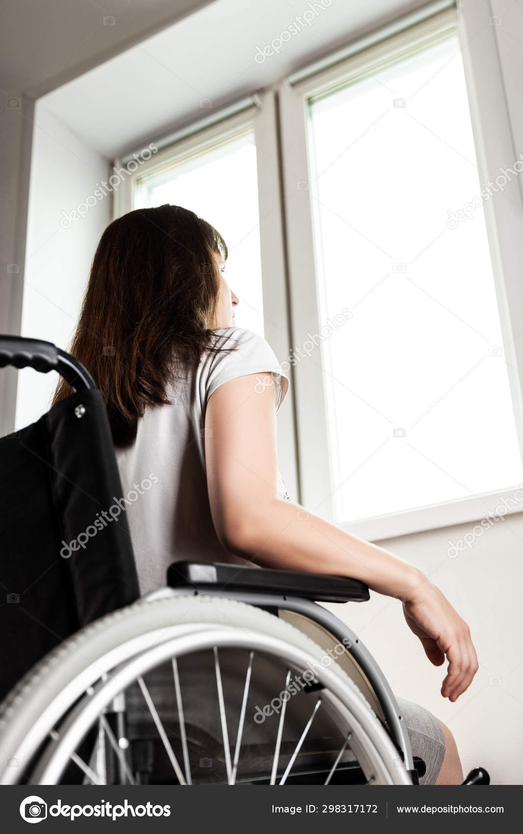 Invalid or disabled woman sitting wheelchair looking window daylight ...