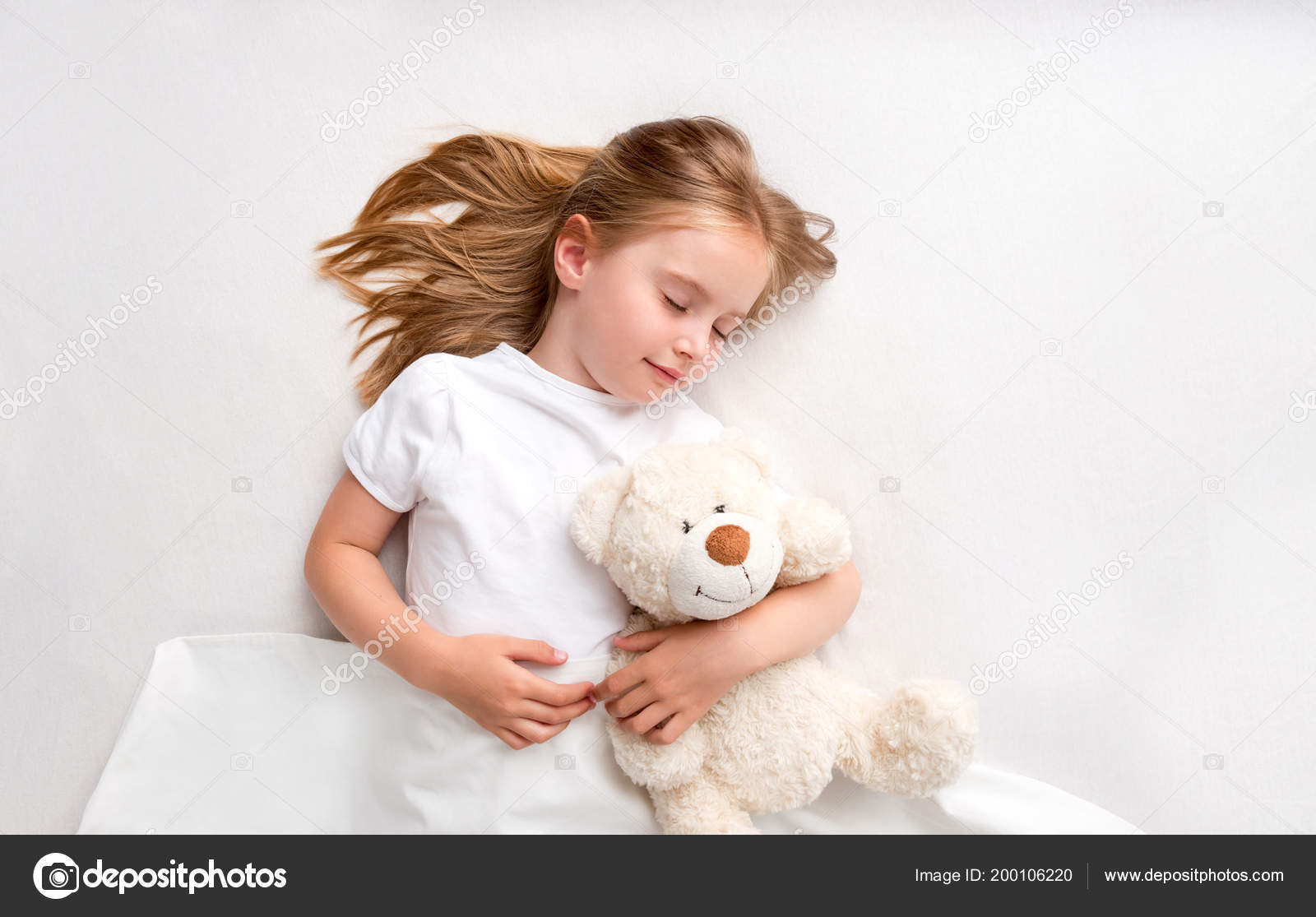 Mädchen umarmt Teddybär, der auf dem Bett liegt - Stockfotografie ...