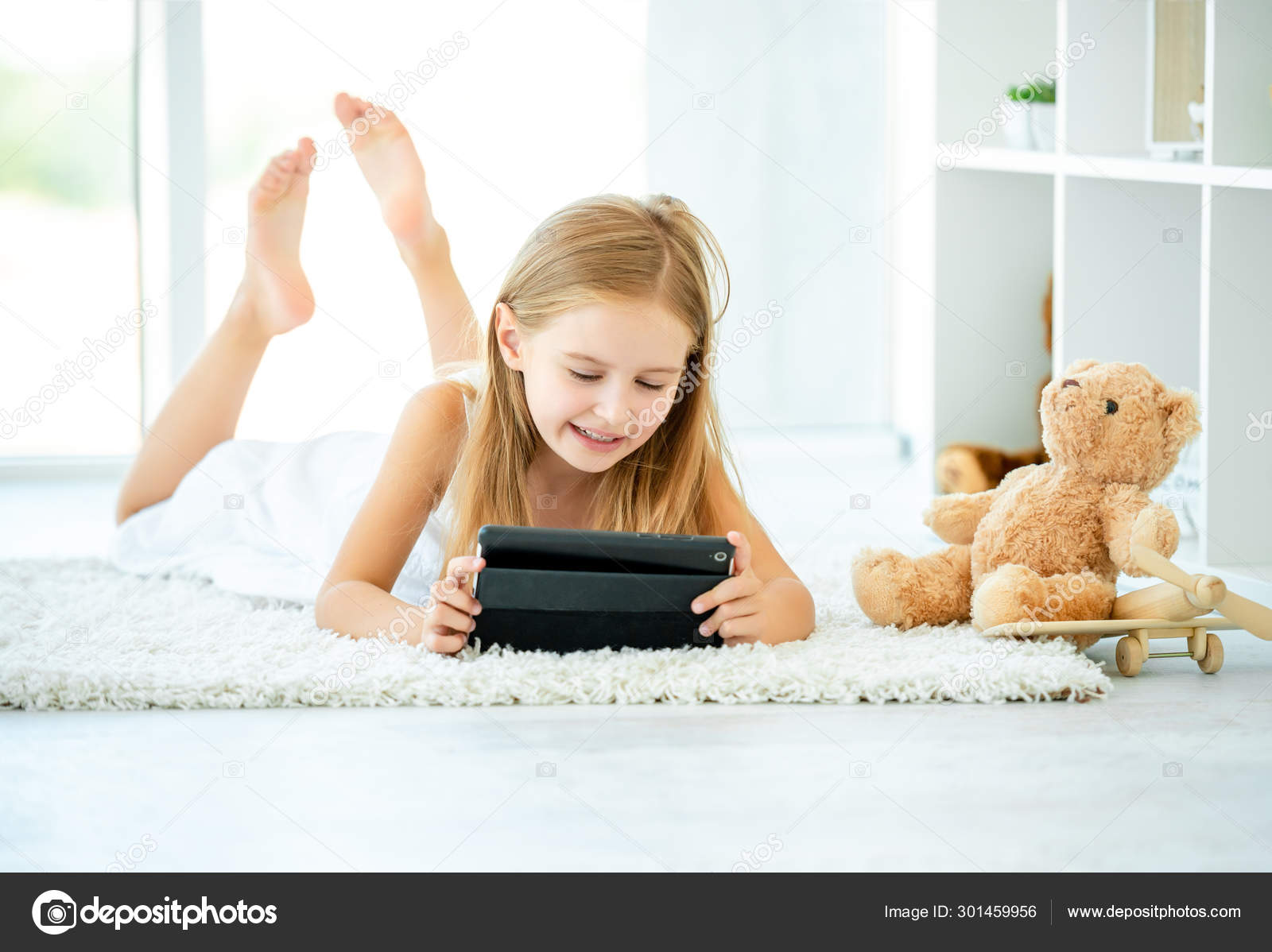 Little girl playing on her tablet — Stock Photo © tan4ikk #301459956