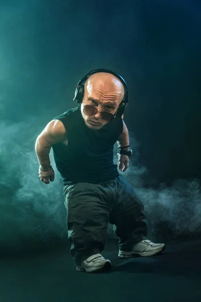 Portrait of stylish midget MC in with headphones and sunglasses posing ...