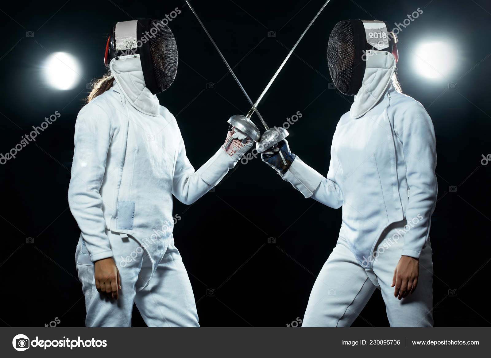 Young fencer athlete wearing mask and white fencing costume. holding the sword on black ...