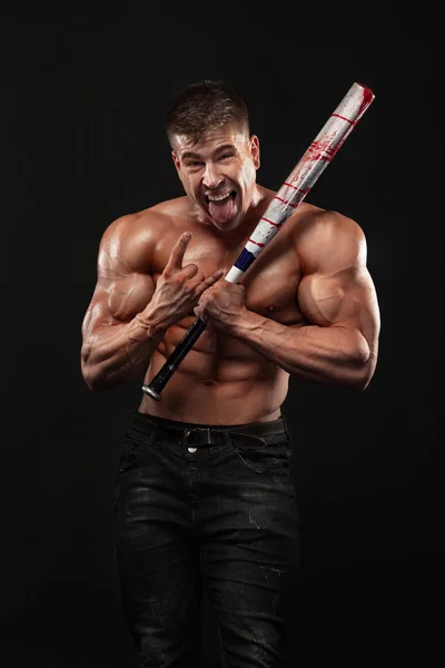 Strong and fit man bodybuilder with baseball bat shows abdominal ...