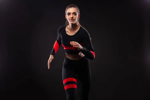 Strong athletic woman sprinter, running on black background wearing in ...