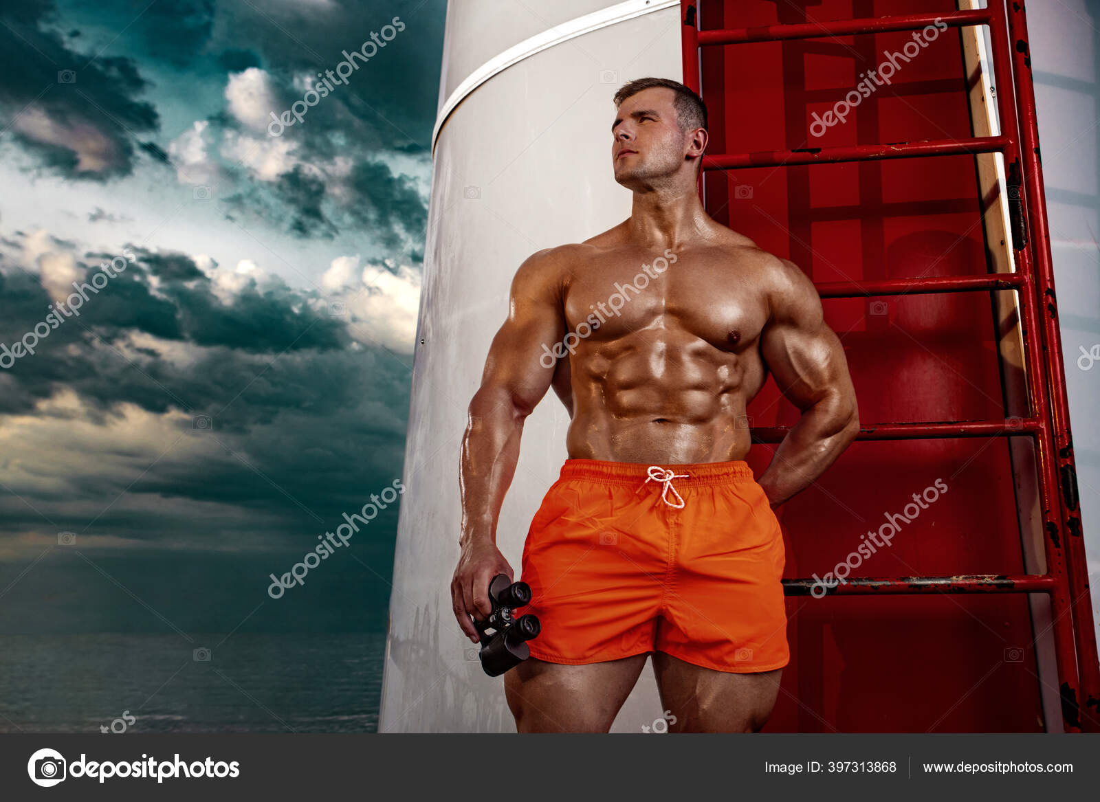 Fit Athlete Bodybuilder With Binoculars In Hand On The Beach