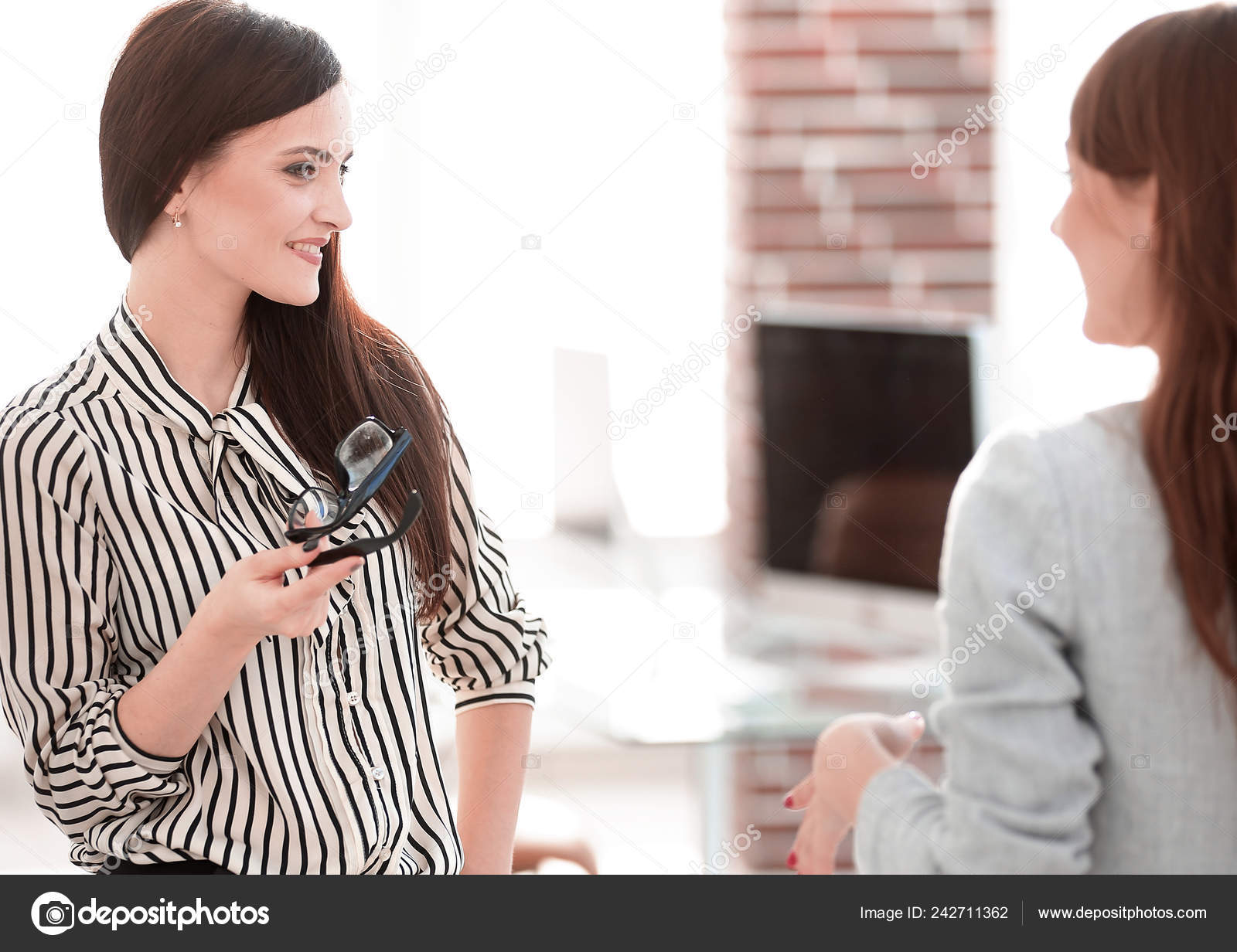 Two young employees are talking in the office. Stock Photo by ...