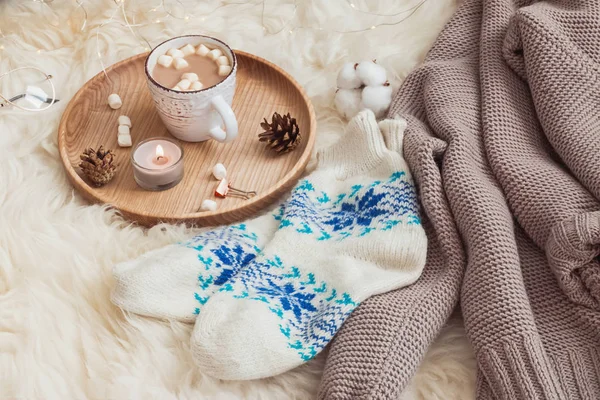 Cozy winter still life. Socks, sweater and hot cocoa on the fur rug ...