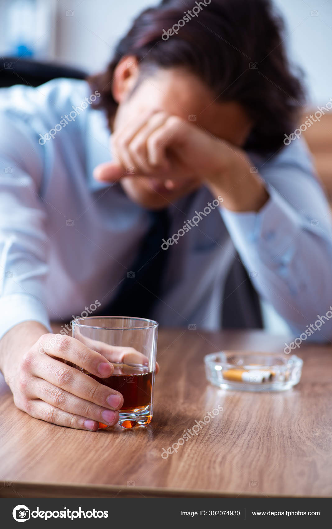 Male employee drinking alcohol and smoking cigarettes at workpla ...