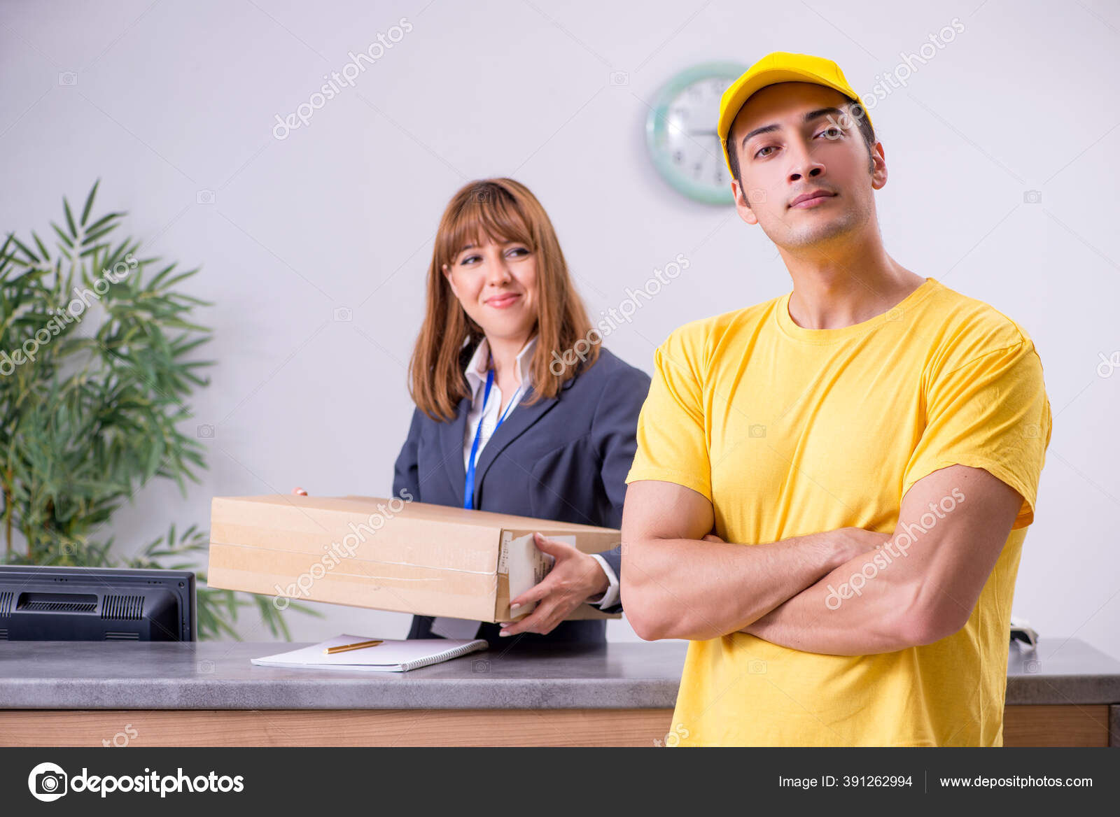 Young male courier delivering box to hotels reception — Stock Photo ...