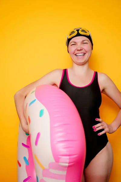 Photo of woman in swimming goggles, black swimsuit with yellow lifebuoy ...
