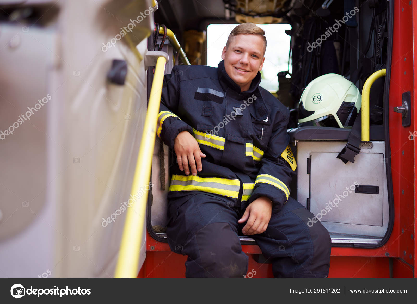 Image of smiling fireman sitting in fire truck at fire station Stock ...