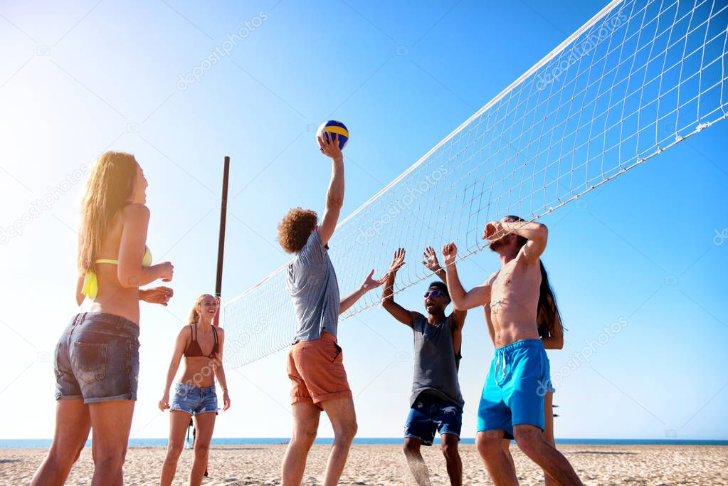 Grupo de amigos jugando al voleibol en la playa 2023