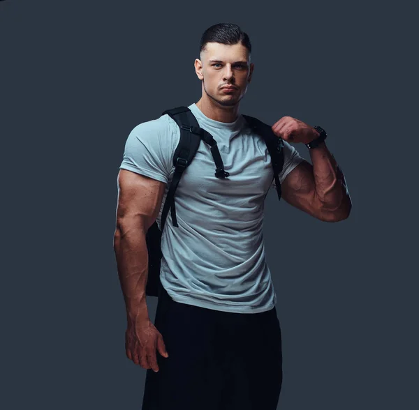 Muscular handsome bodybuilder in sportswear with rucksack posing ...