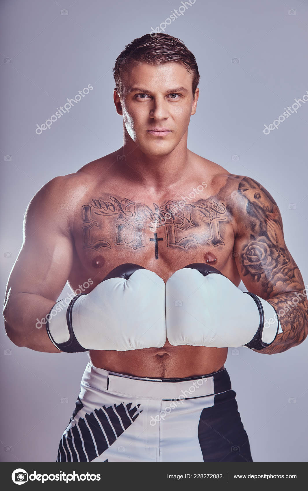 Brutal tattooed boxer in boxing gloves posing for a camera, isolated on ...