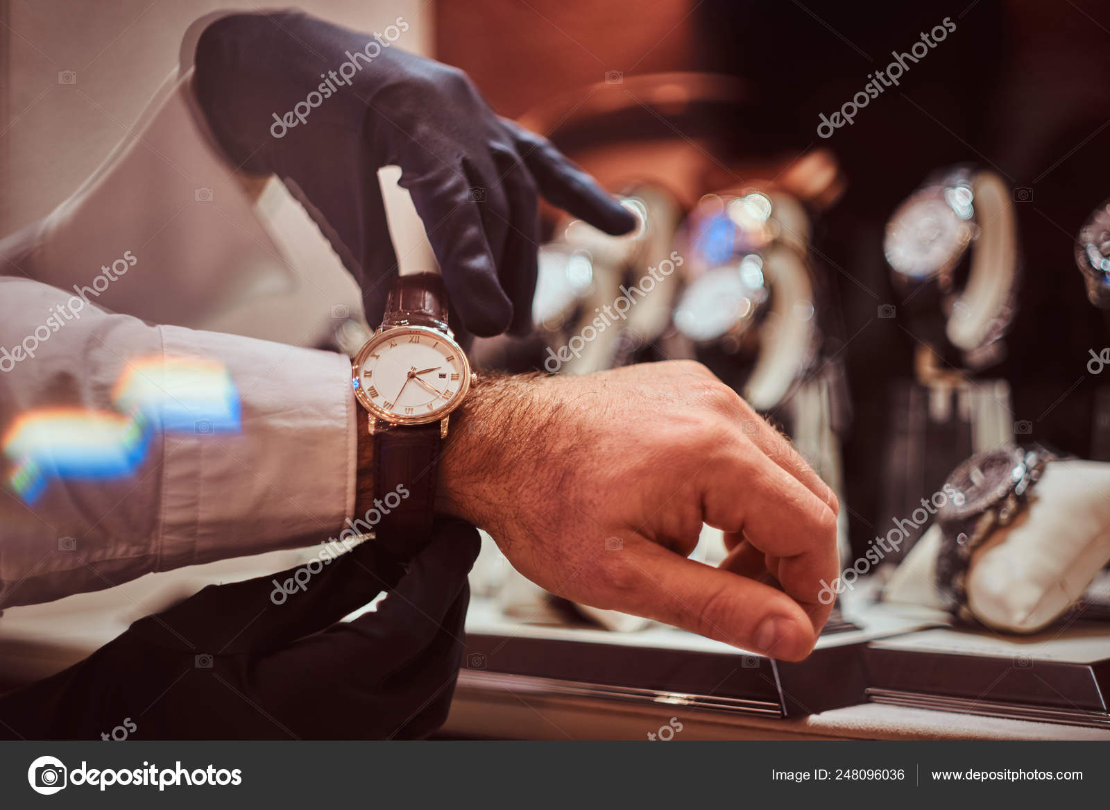 Close-up hands. Assistant helps the client to try on exclusive mens ...