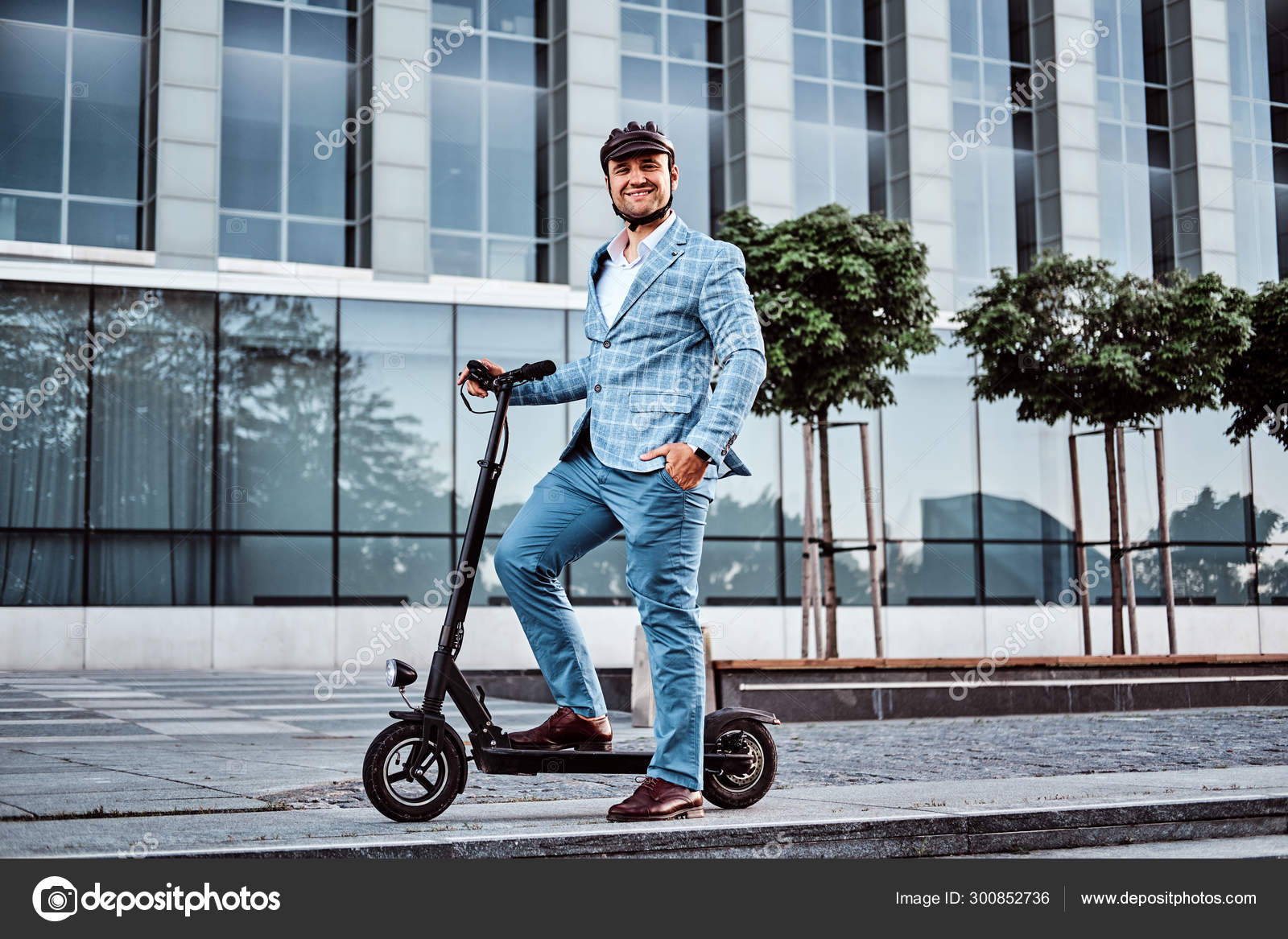 Handsome man is riding his scooter near offices building Stock Photo by ...