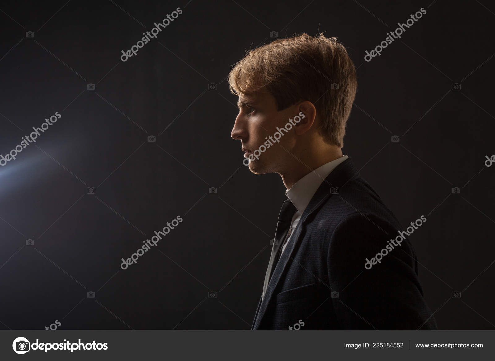 Profile of a young man in a business suit on a black background. Stock ...