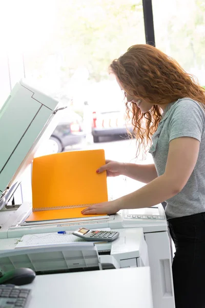 A young student at a copy center taking some copies for her final exams ...