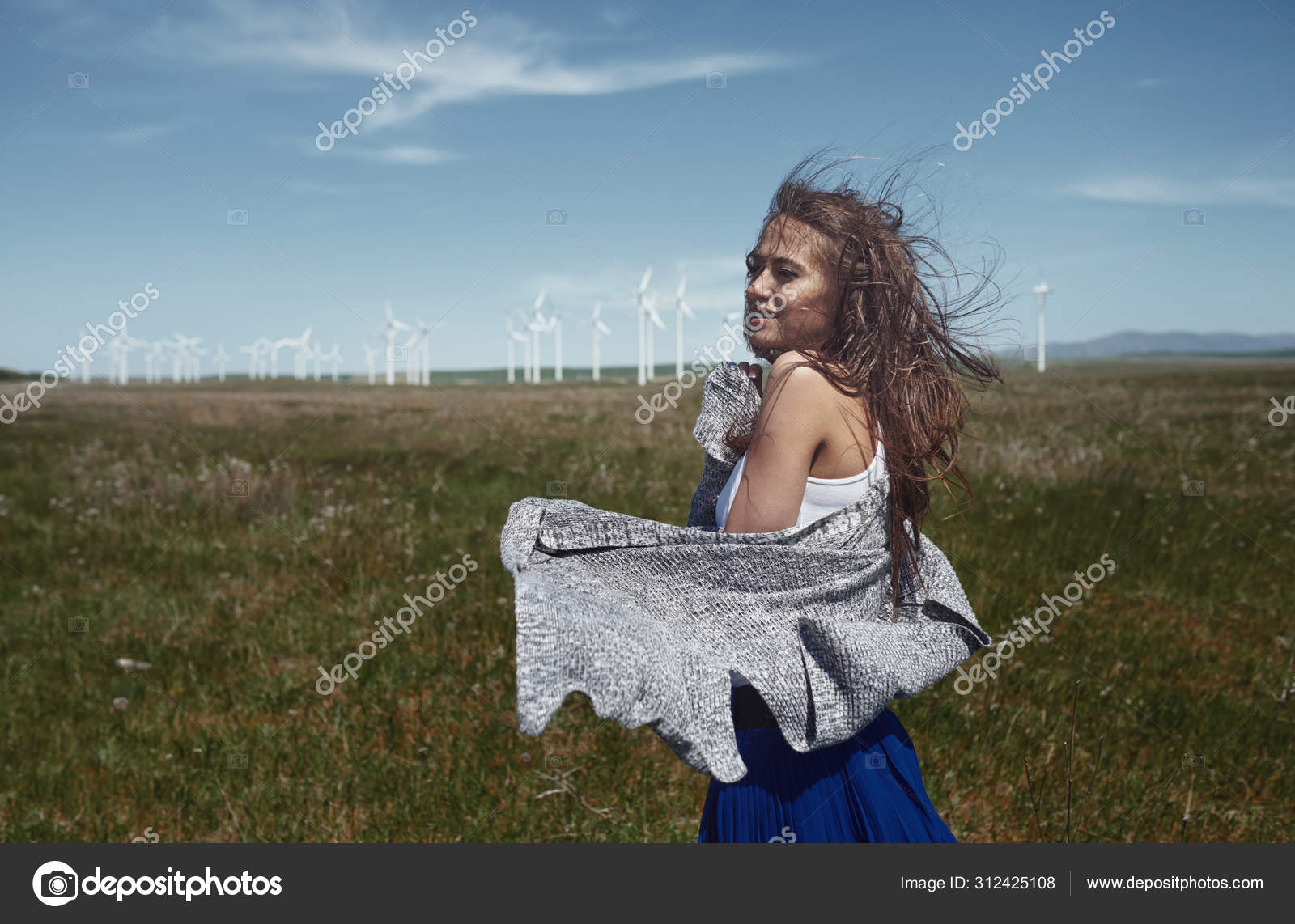 Woman with long tousled hair next to the wind turbine with the w ... Woman with long tousled hair next to the wind turbine with the w ...