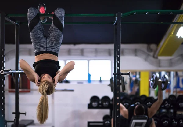 athlete woman doing abs exercises hanging upside down on horizontal bar ...