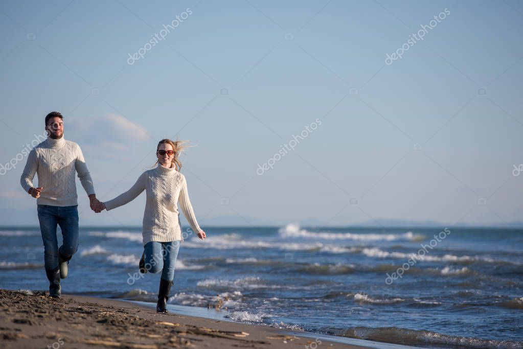 Pareja joven divirti ndose caminando y abraz ndose en la playa durante el d a soleado de oto o 2024