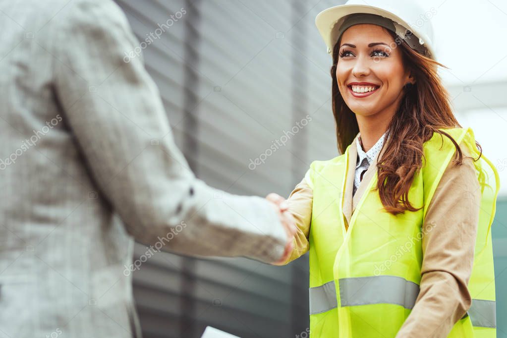 Joven ingeniera exitosa en casco blanco estrechando la mano con el ...