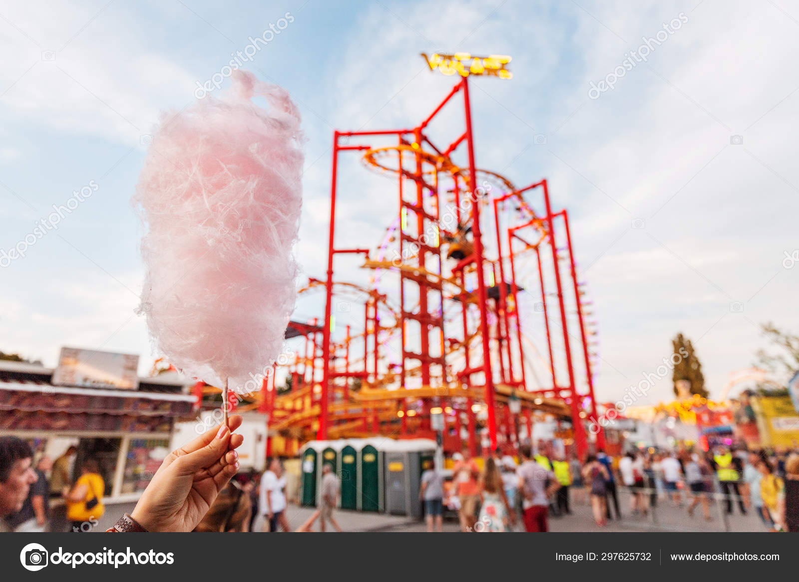 Candy cotton in hand at the background of amusement park and roller ...