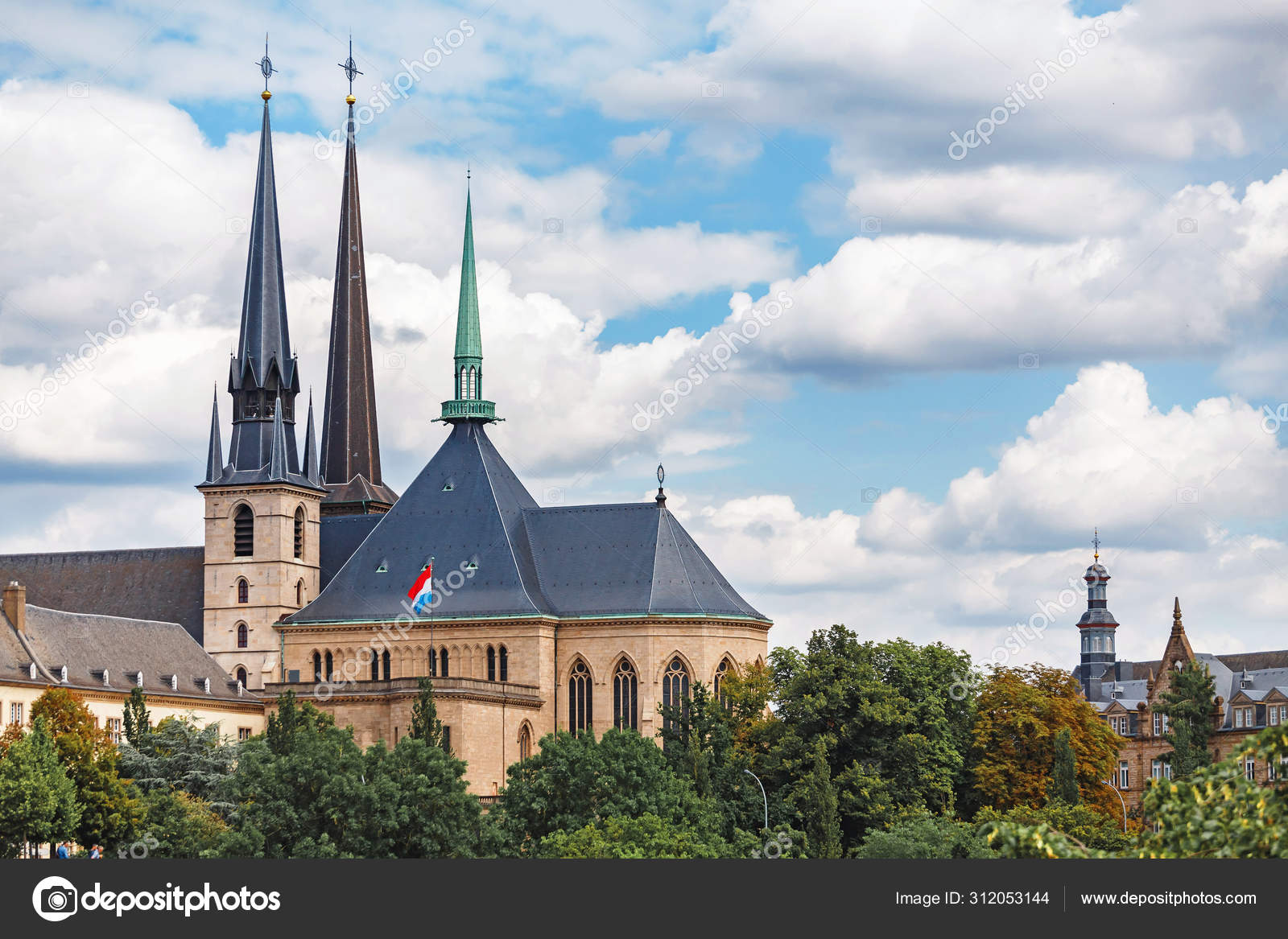A classic view of the Notre-Dame Cathedral in Luxembourg with high spires and the flag of the ...