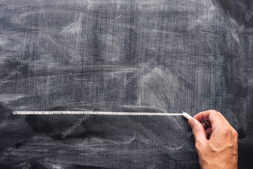 Mano subrayando con tiza en pizarra escolar. Profesor enfatizando algo ...