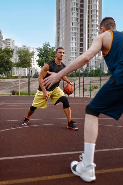 Two basketball players work out tactics on outdoor court. Male athletes ...