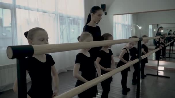 The strict female teacher of dance class correct position of little ...