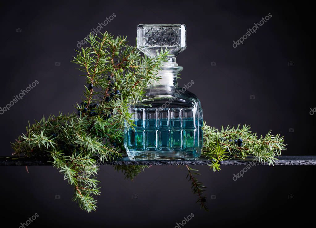 Ginebra azul en decantador de cristal y rama de enebro con bayas sobre ...