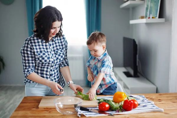 mom and son cooking vegetables at table in kitchen - Stock Image ...
