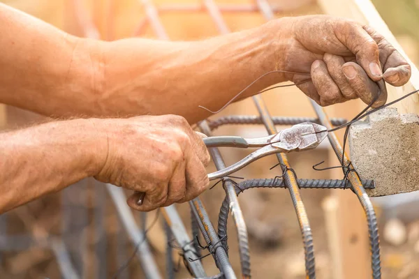 Details of construction worker - hands securing steel bars with wire ...