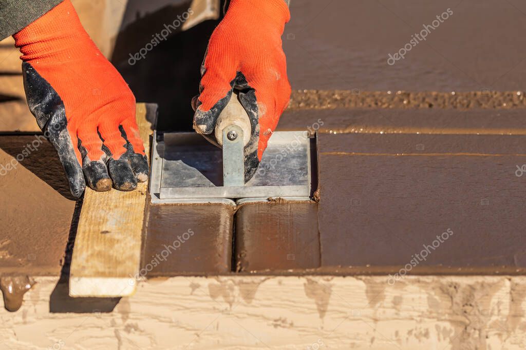Trabajador de la construcción usando la mano Groover en el cemento ...