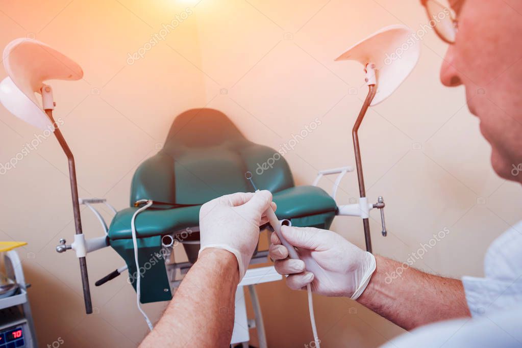 Proctólogo sosteniendo un anoscopio contra una silla proctológica. En ...