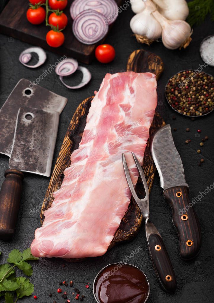 Costillas frescas de cerdo crudo sobre tabla de cortar y tenedor de ...