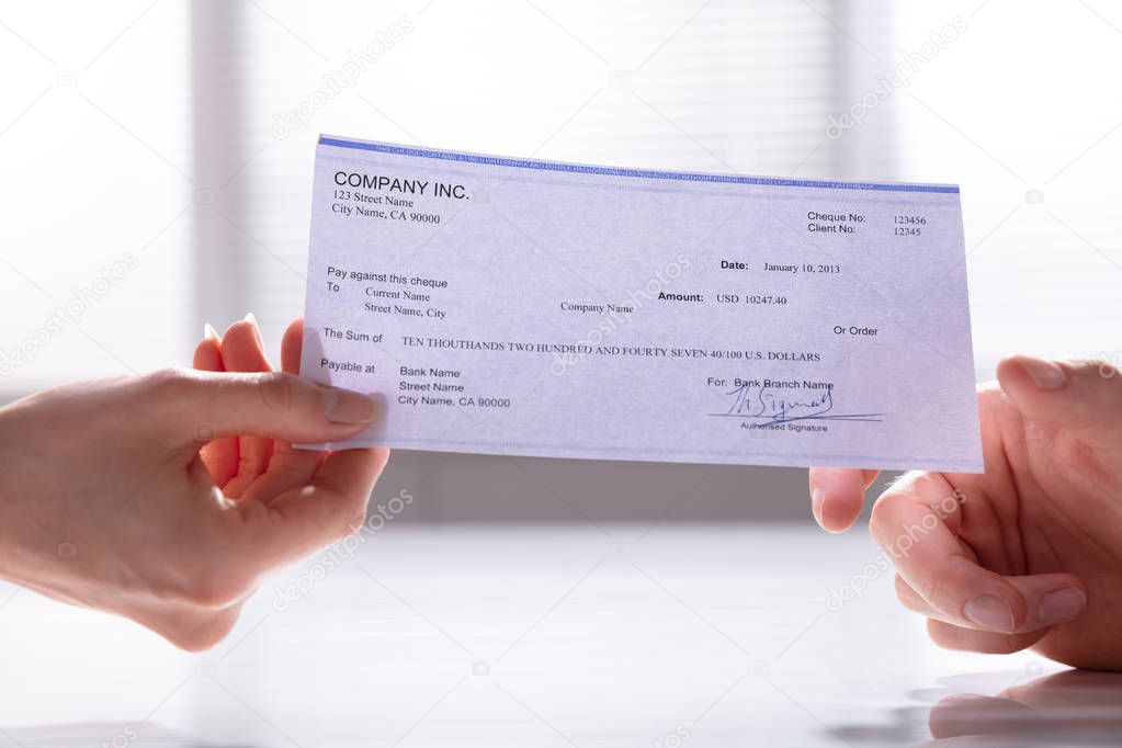 Primer plano de la mano de la mujer sosteniendo el cheque y dando al ...