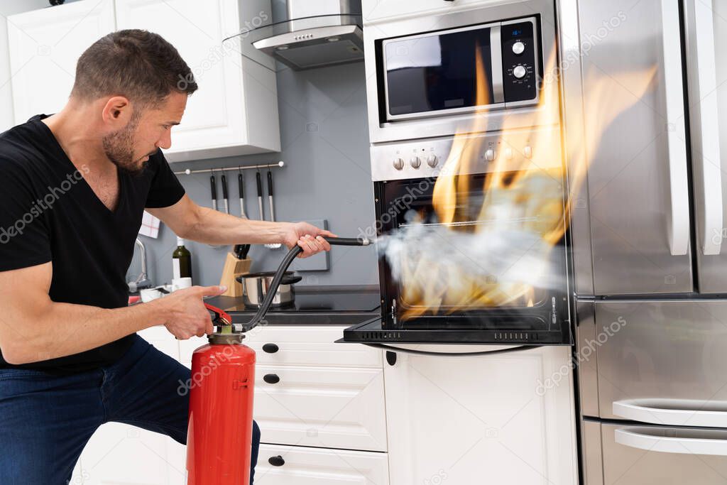 Hombre usando extintor de fuego para apagar el fuego del horno en casa 2022