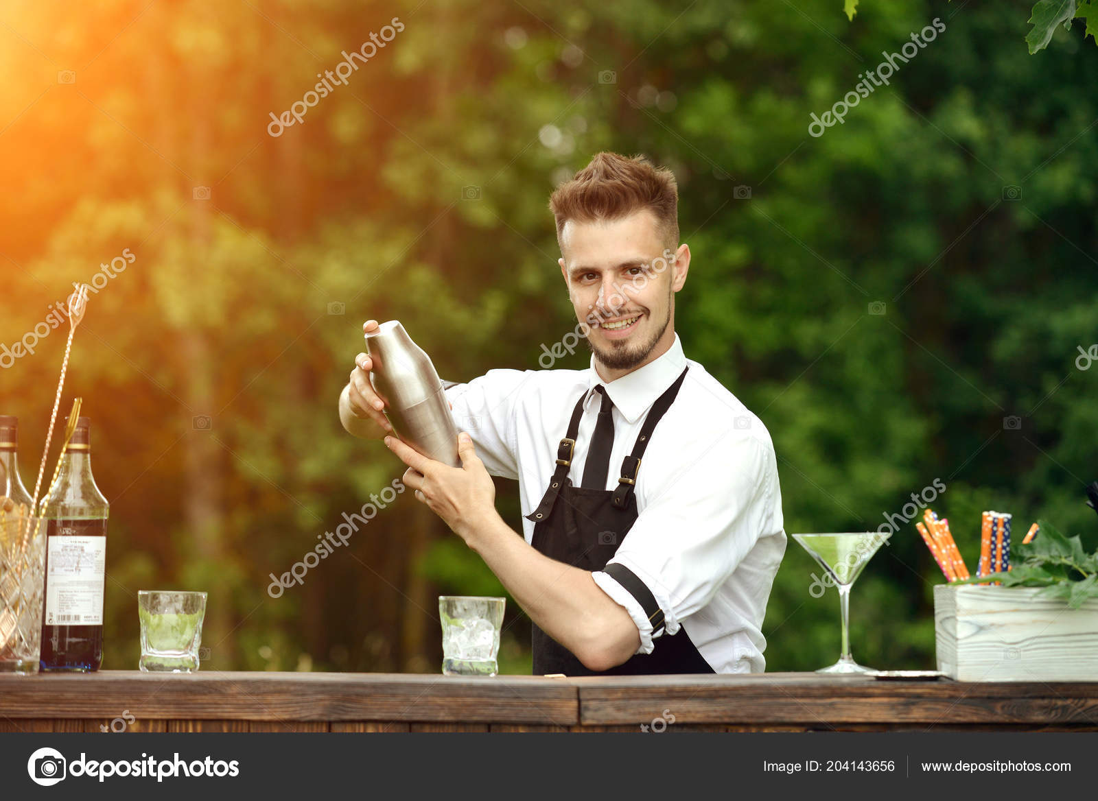 Handsome smiling barman shaking and mixing cocktail outdoors, ca Stock ...