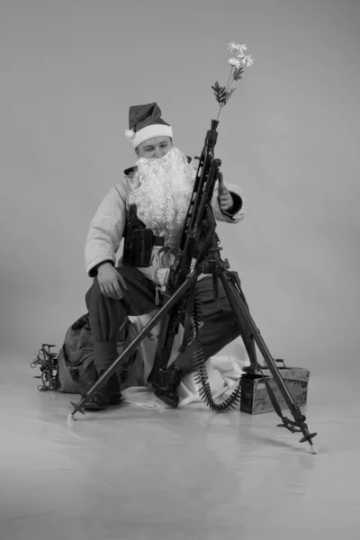 man actor in a Santa Claus hat in old military clothes sits next to a ...