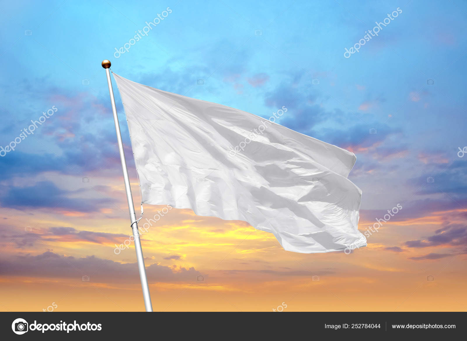 Blank white flag on pole waving in the wind in the background of sunset ...
