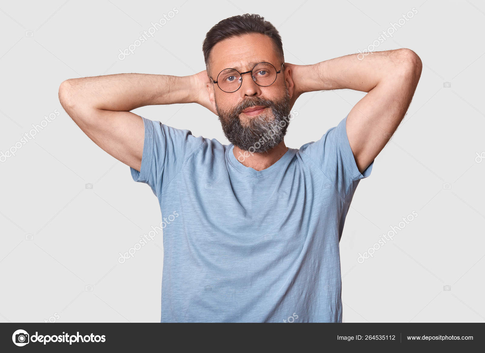 Confident relaxed calm man rises his arms, touching his head with both ...