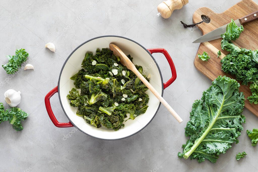 col rizada salteada con ajo en sartén de hierro fundido en la mesa de ...
