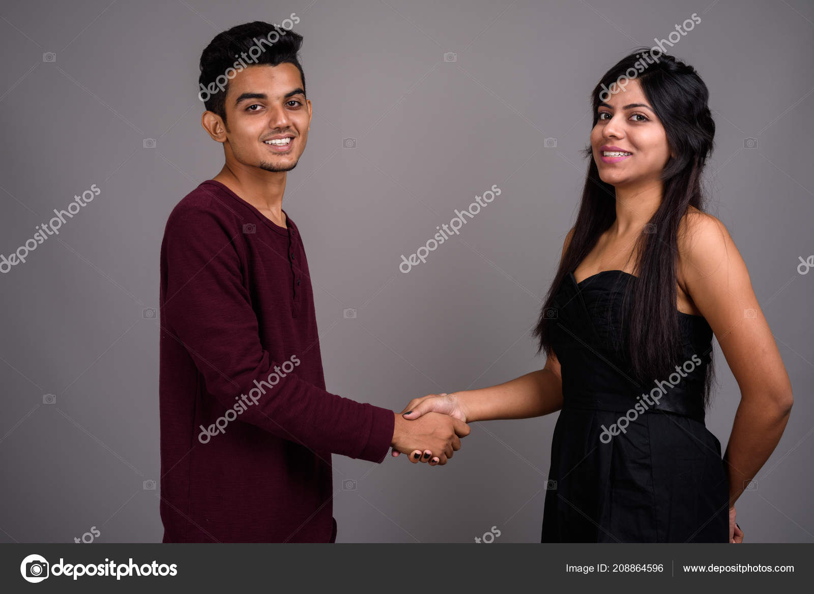Young Indian man and young Indian woman together against gray ba ...
