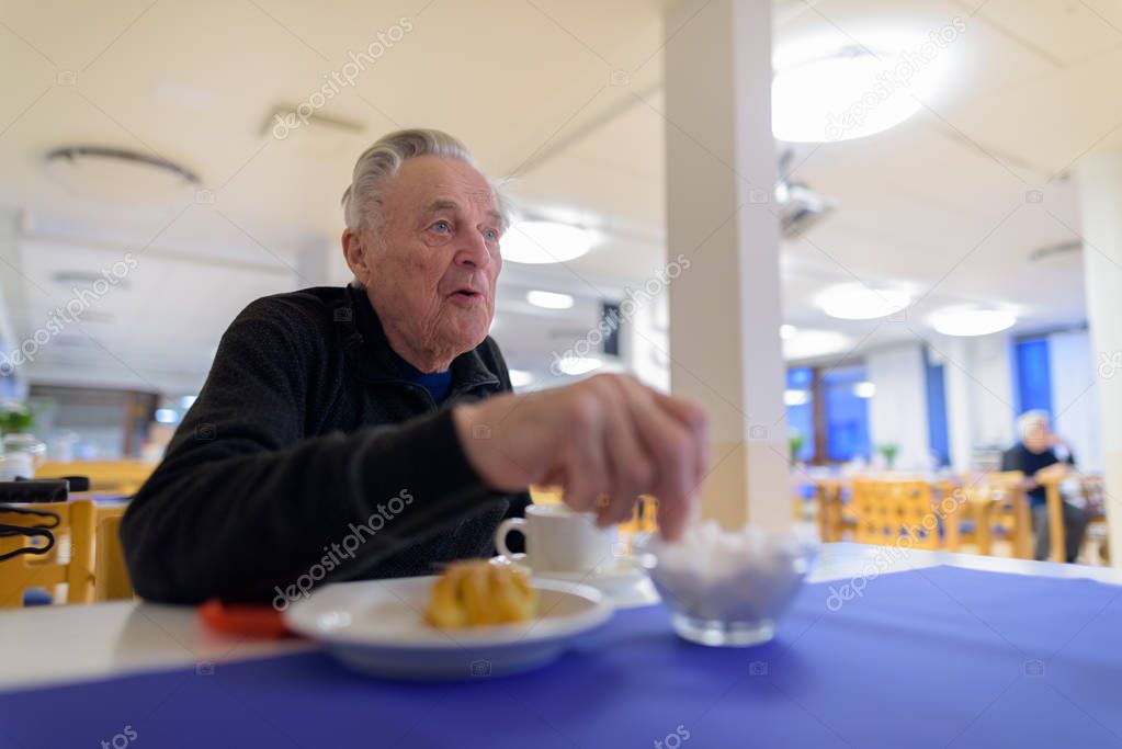 Hombre mayor comiendo en la cafetería del asilo 2023