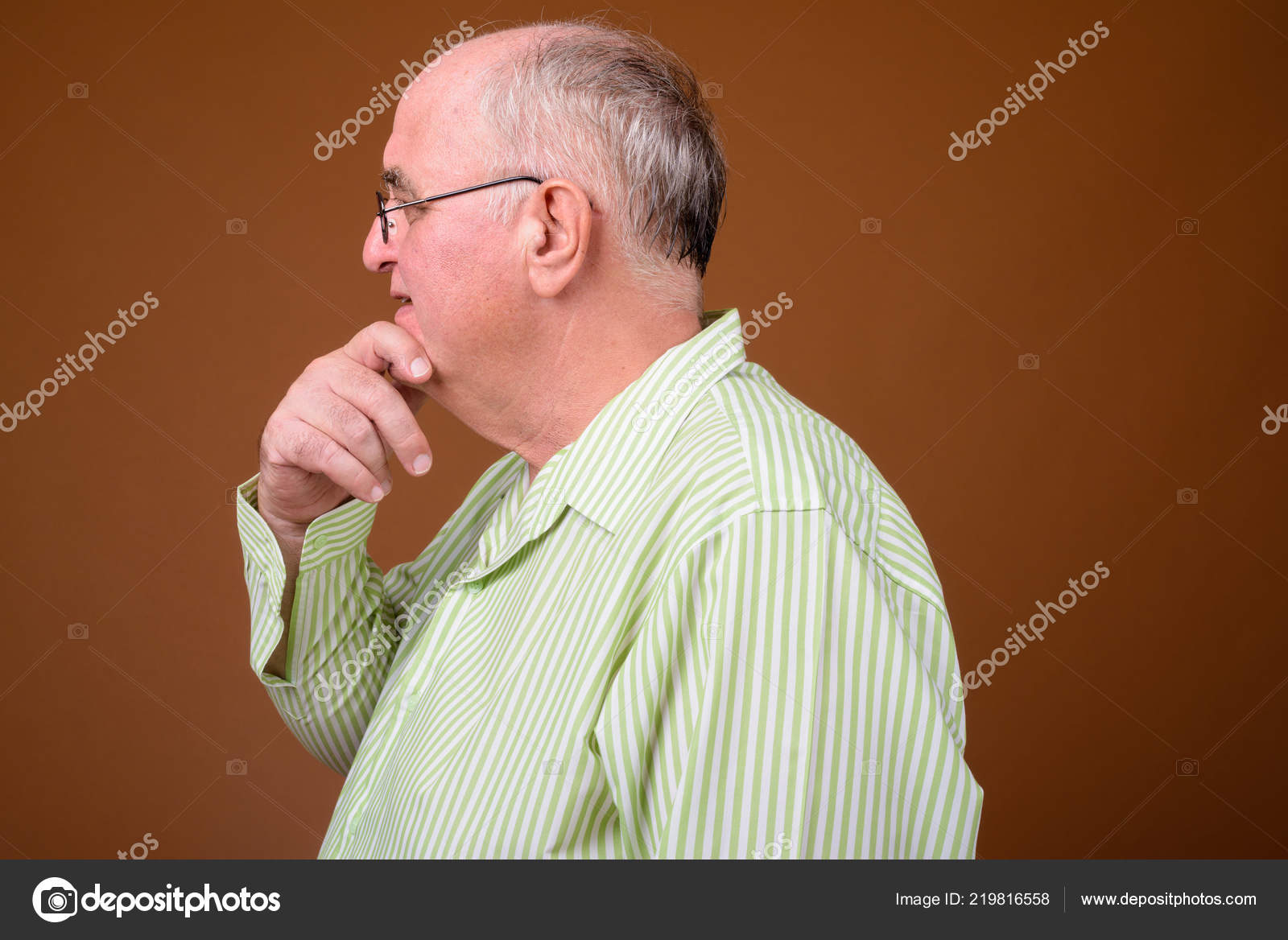 Overweight senior man wearing eyeglasses against brown backgroun ...