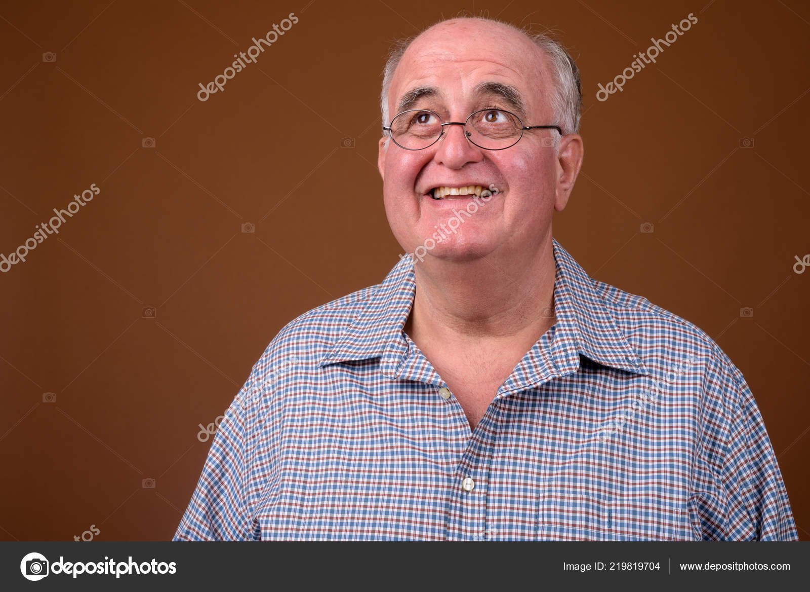 Overweight senior man wearing eyeglasses against brown backgroun ...