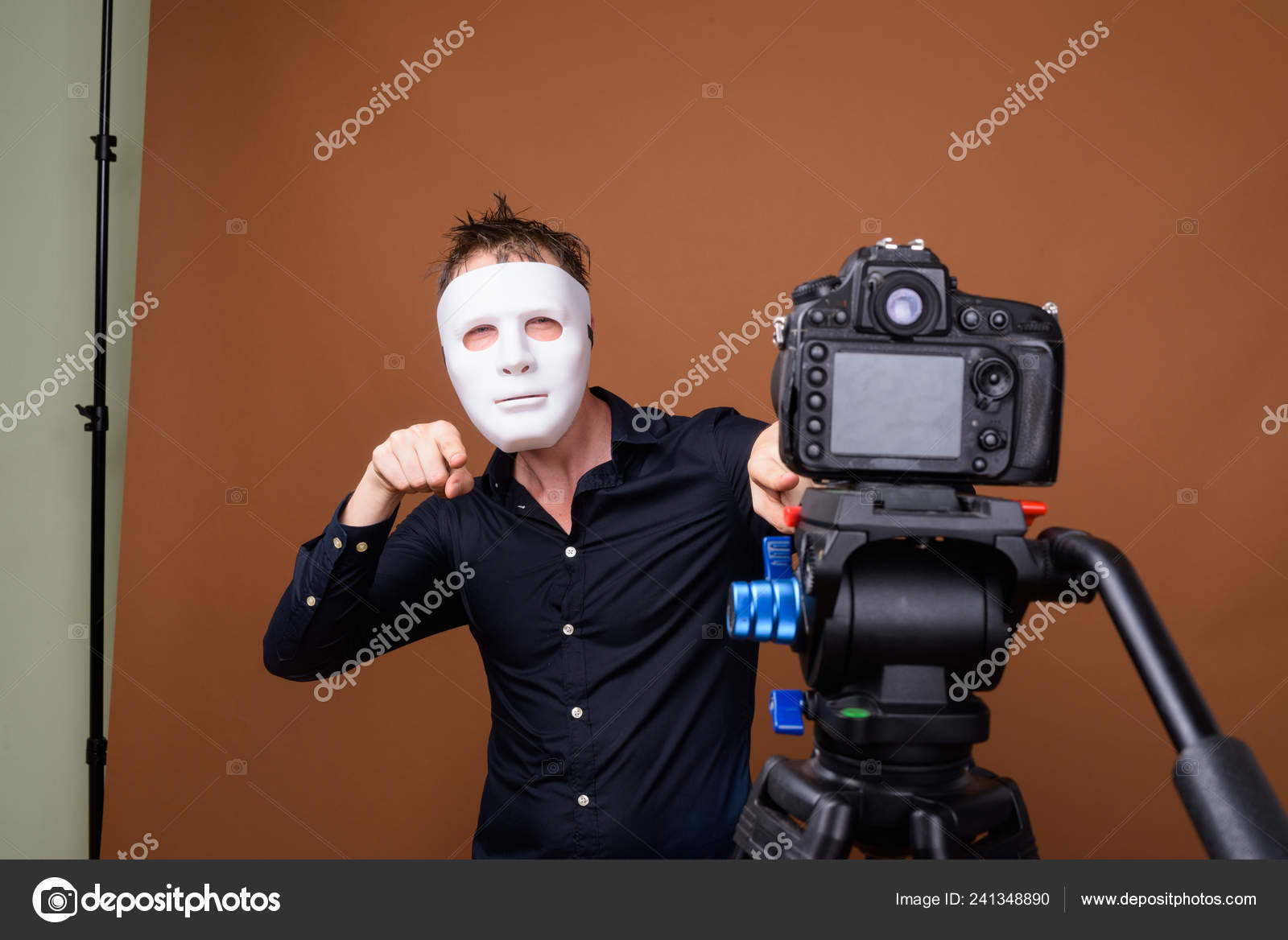 Young man influencer wearing mask while vlogging with camera in studio ...