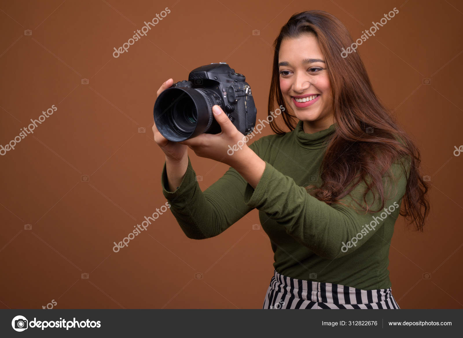 Young beautiful Indian woman with camera against brown backgroun Stock ...